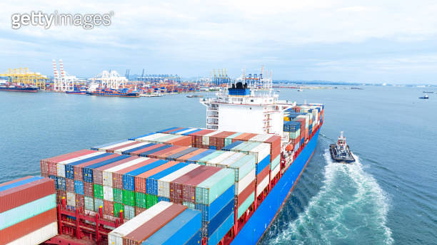 Cargo container ship carrying container and running with tug boat for ...