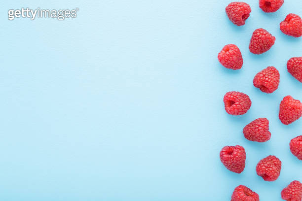 Fresh red raspberries on light blue table background. Pastel color ...