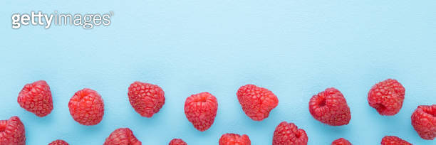 Fresh red raspberries on light blue table background. Pastel color ...
