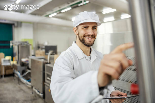 A happy meat factory supervisor is touching display on a meat ...