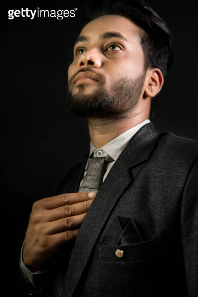 Low key portrait of handsome Indian young businessman contemplating ...