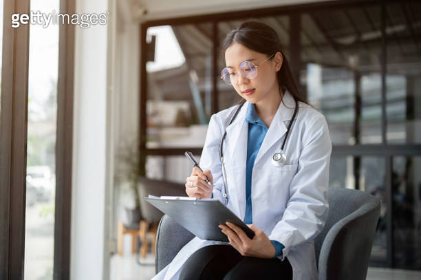 A professional Asian female doctor is reading and examining her medical ...