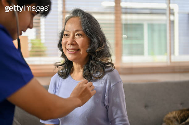 60-year-old Asian retried woman is being measured for her heart beat by ...