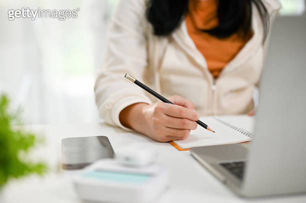 Cropped image of an Asian female college student doing homework ...