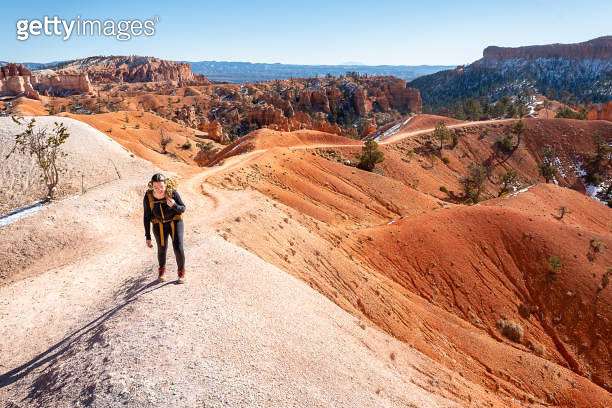 Female hiker climbing around Bryce national park sand dunes on a bright ...