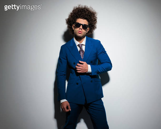 sexy high class man with afro hair arranging blue suit and posing in a ...