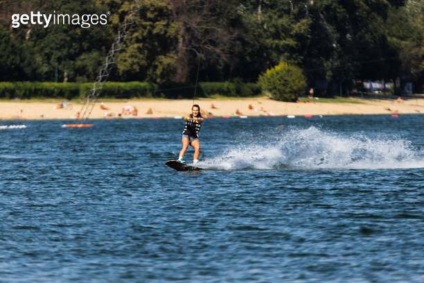 Female wakeboarder wakesurfing. Girl riding waterski cabel. Holding tow ...