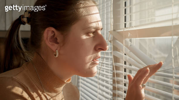Young woman saw crime happening on street through window blinds. Crime ...