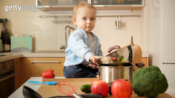 Cute little baby boy playing with metal pans, glass lids and bowl on ...