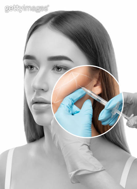 The cosmetologist makes injections of the cheekbones of a beautiful ...