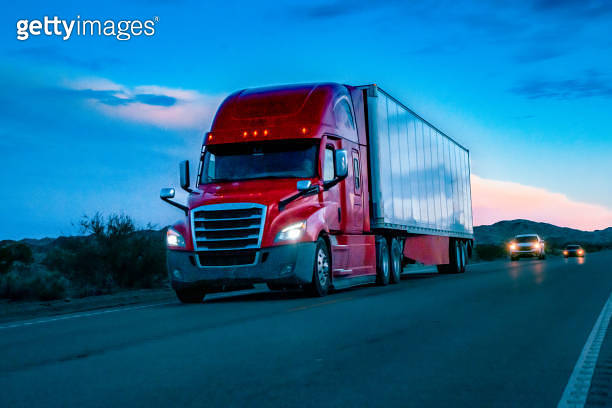 At sunset, a mighty semi truck rolled through the Nevada desert, its ...