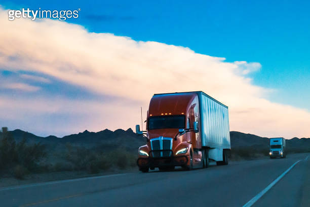 Against the backdrop of a sunset sky, a semi truck traversed the Nevada ...
