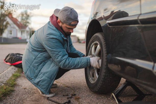 Close-up of a young man removing his car tire 이미지 (1752606816) - 게티이미지뱅크