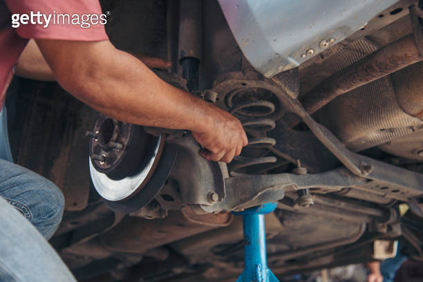 Close up Mechanic man hands repairing car auto repair shop uses jack ...