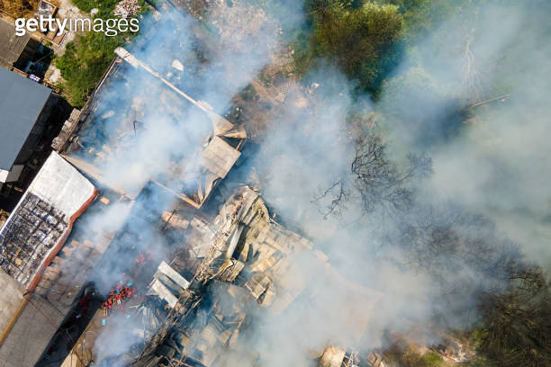 Aerial view of ruined building on fire with collapsed roof and rising ...