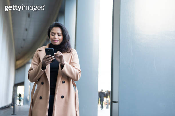 Mid adult woman using a smart phone outside a modern city building 이미지 ...