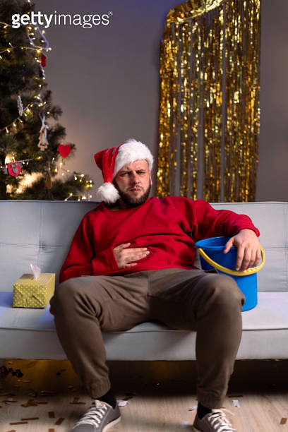 Bearded man wearing Santa hat suffering from sick stomach and vomiting ...