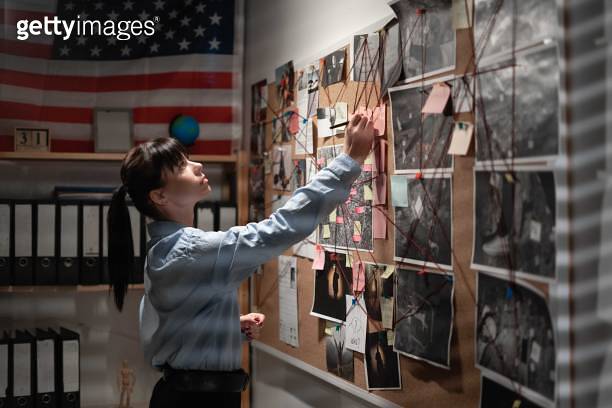 Young Detective looking at investigation board, searching for solution ...