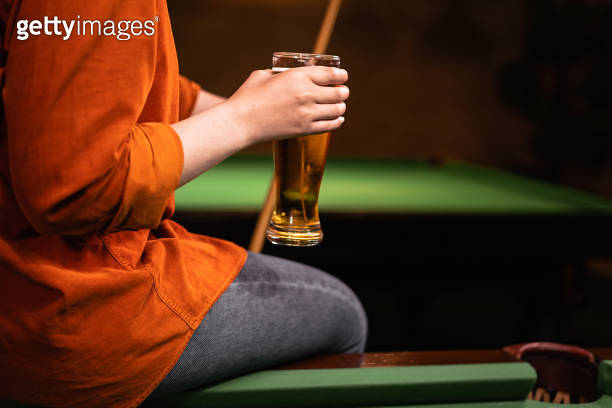 Female evening in billiard club. Girl drinking beer beside billiard ...