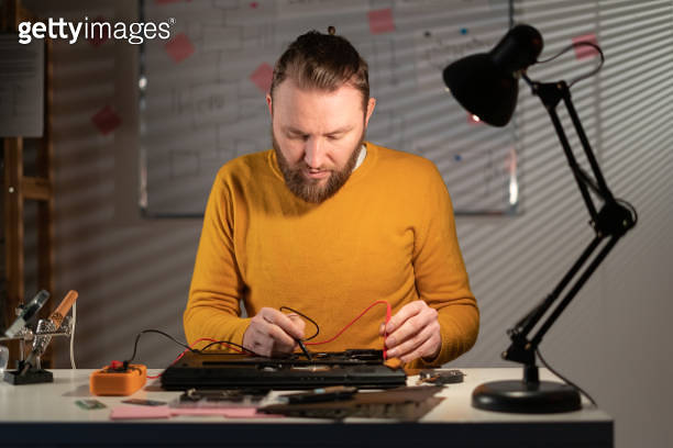 Engineer diagnosing laptop computer using multimeter, repairing broken ...