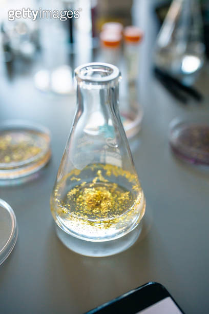 Erlenmeyer flask with golden glitter sample mixed in analysis liquid ...