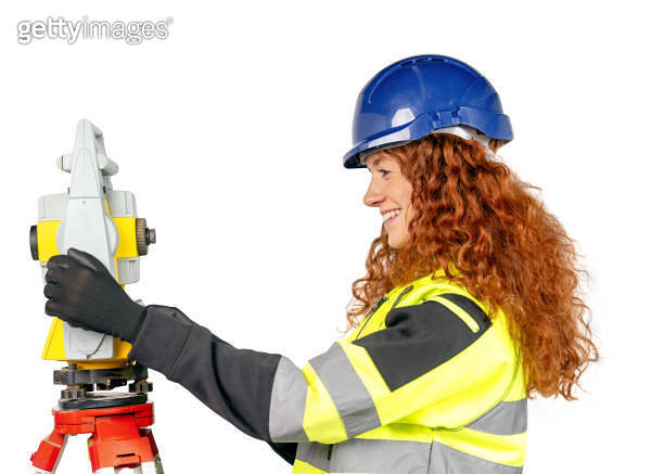 Smiling Woman in hard hat and protective clothes land surveyor working ...
