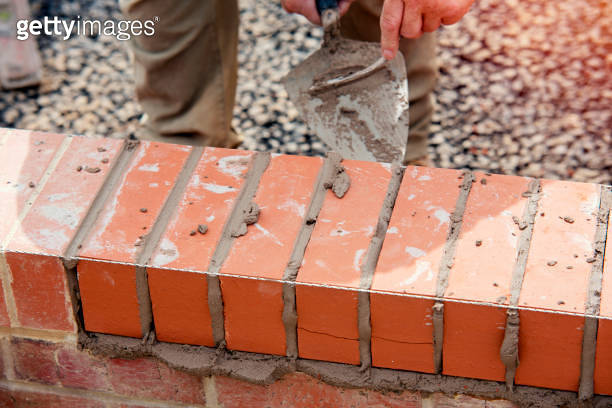 Close up of a brick wall and jointer trowel used by the worker to apply ...