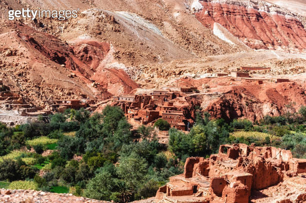 Small Berber village located in a green oasis valley with fields and ...