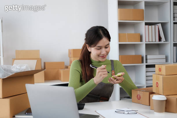 Young Asian small business shop owner writing customer details ...