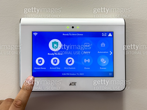 A person using an ADT security touch screen panel control on a wall ...