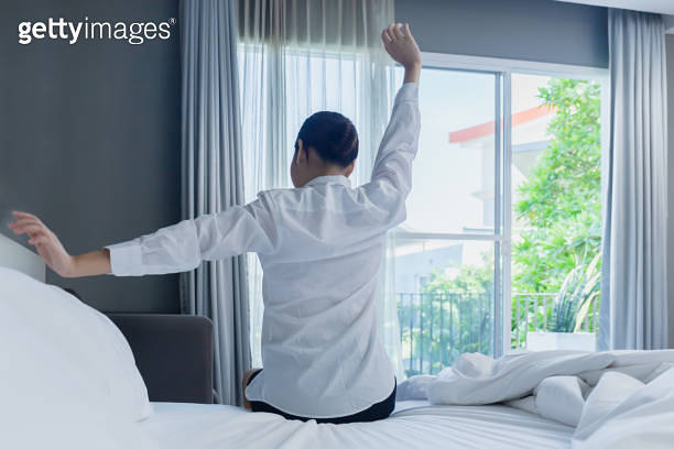 Back view of woman wake up in the morning and stretching hand on the ...