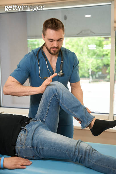 Physiotherapist assessing lower limb muscle strength in patient ...