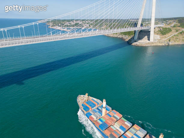 Aerial view of a cargo container ship passing under bridge. Istanbul ...