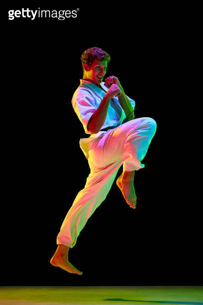 Knee kick. Young man in white kimono practicing karate punches, kicks ...