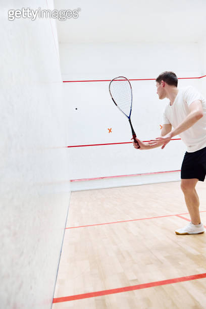 Young sportive man playing, training squash on squash court. Hitting ...
