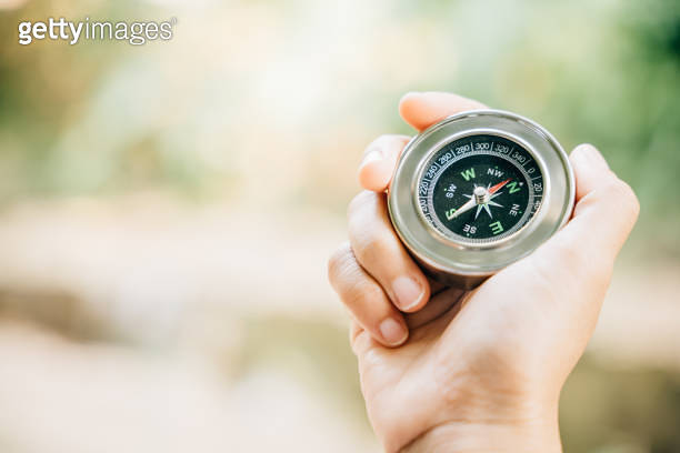 Hiker searches for direction in the forest holding a compass to ...