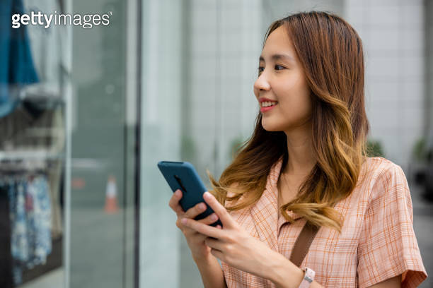 woman scrolling through her phone with a smile on her face outdoor 이미지 ...