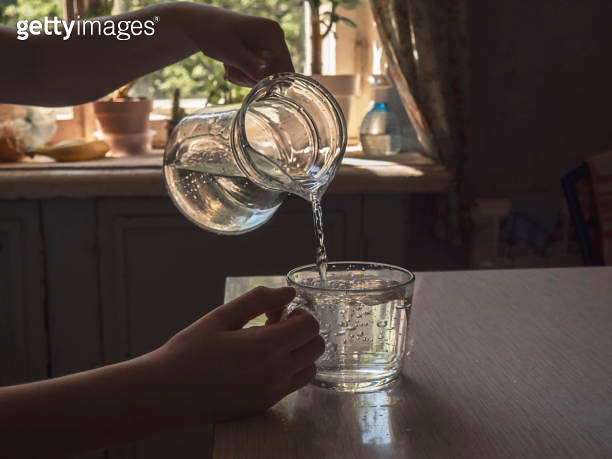 Man's hands pouring water from a pitcher into a glass. Lifestyle, art ...