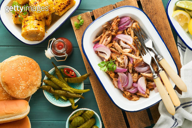 Pulled bbq chicken with baked onions on serving platter, bbq corn ...