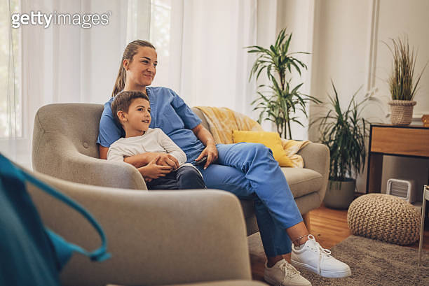 Female nurse came back from work and still wearing scrubs relaxing at ...