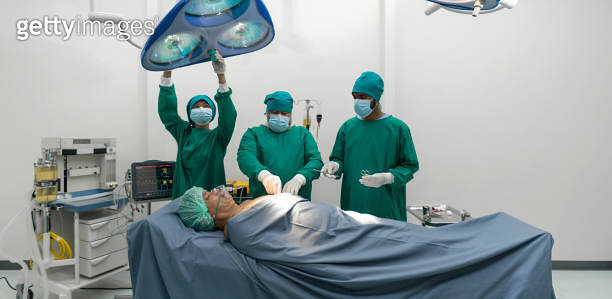 Group of surgeons, steeped in concentration, performing complex surgery ...