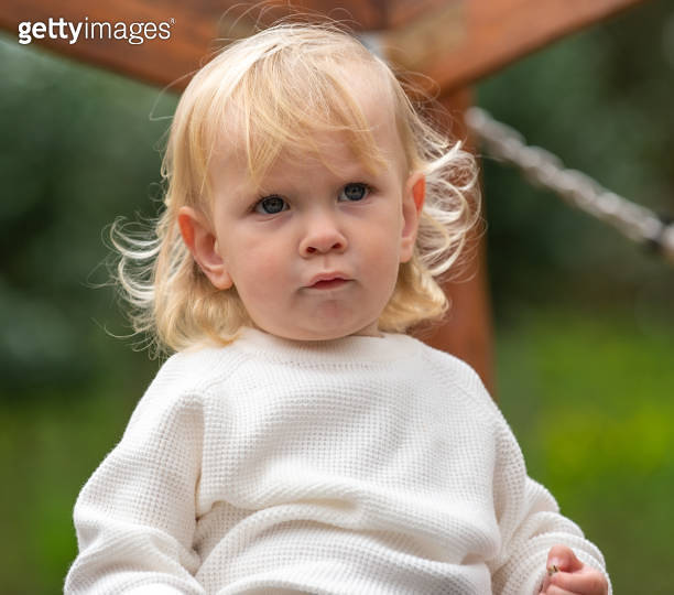 Thinking child sitting outdoors on a spring day. Cute blonde kid ...