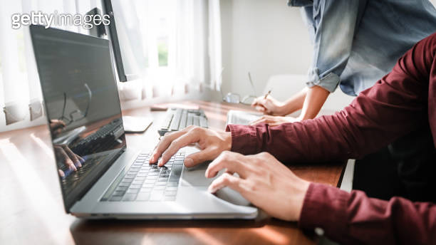 programmer writing program code with two monitors and working on a new ...