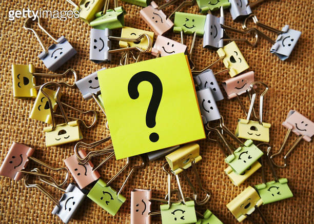 Question marks piled up on burlap background with funny paper clips ...