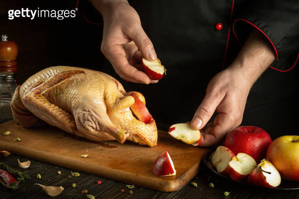 The cook adds apples to raw duck before roasting in the oven. Cooking a ...