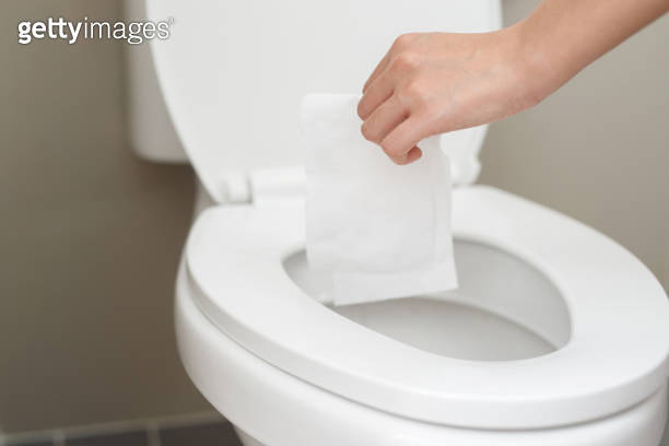 close up hand holding a tissue to be thrown into the toilet bowl. Can ...