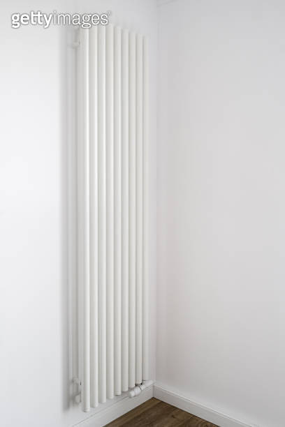 Vertical radiator install on white wall in empty room with minimalist ...