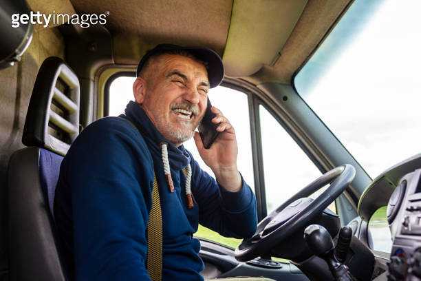 Mature truck driver using mobile phone while driving transport vehicle ... Mature truck driver using mobile phone while driving transport vehicle ...