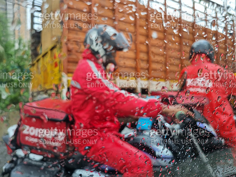 Zomato food delivery riders wearing raincoat delivering in rain for the ...