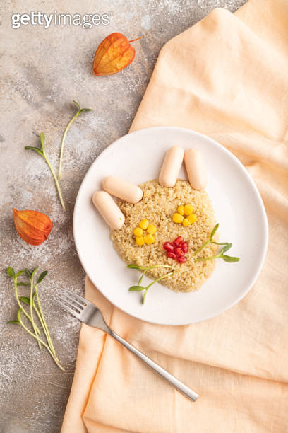 Funny quinoa porridge, and small sausages in form of cat face on brown ...
